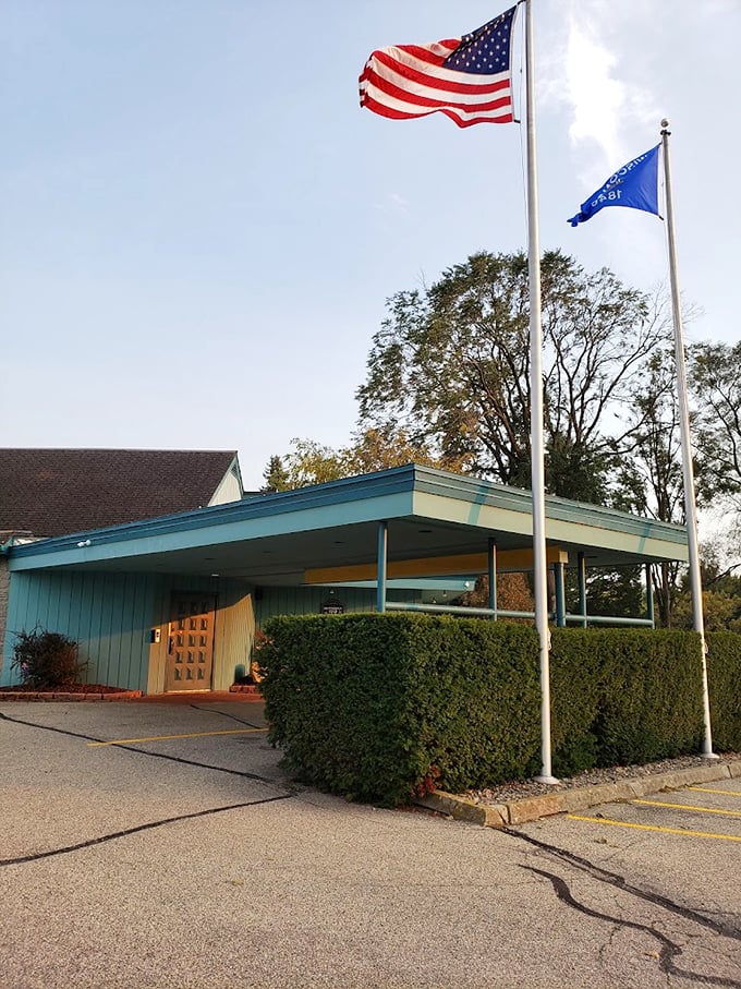 Classic mid-century architecture meets Midwest hospitality under waving flags, where the turquoise trim and manicured hedges welcome diners to this timeless supper club.