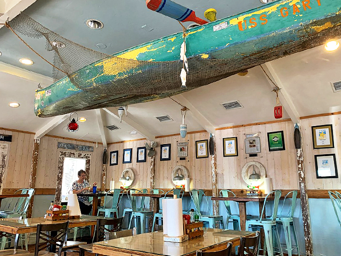 An old fishing boat suspended from the ceiling watches over diners like a guardian of maritime memories.