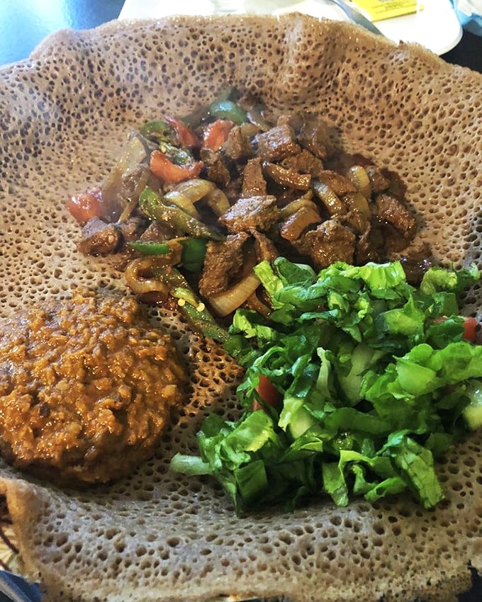 Saut&eacute;ed beef tibsi shares the stage with fresh salad on a canvas of injera. It's dinner and an art piece all in one.