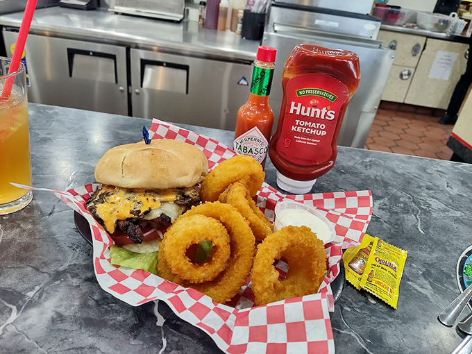 Burger bliss achieved! This juicy masterpiece, flanked by crispy onion rings, is proof that some classics never go out of style. Take that, kale smoothies!