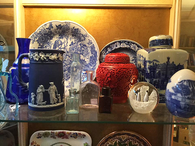 Blue and white porcelain mingle with cinnabar red, creating a sophisticated display of vintage ceramics and glassware.