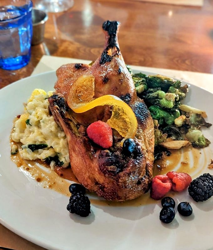 This duck dish is pure theater - golden skin, fresh berries, and a citrus garnish creating a performance worthy of a standing ovation.