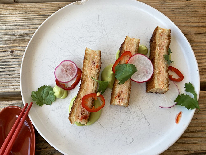 Lobster toast arrives looking like the prom queen of appetizers, dressed with radish rounds and fresh herbs. Photo credit: Rena C.