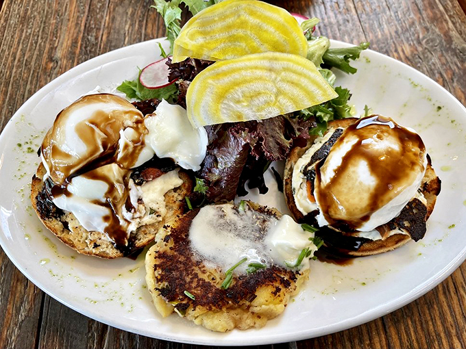 Golden hollandaise cascades over poached eggs like a breakfast waterfall, accompanied by a garden-fresh salad.