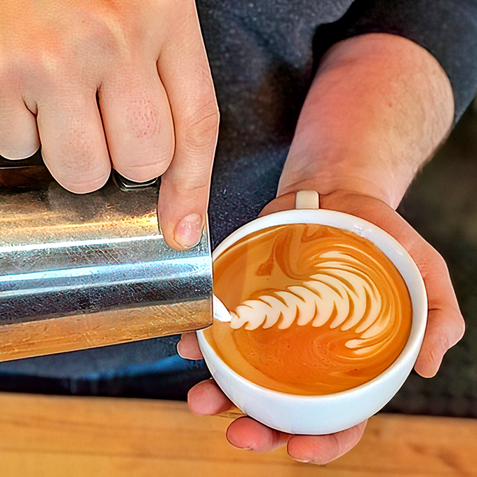 Witness the dance of milk and espresso! This barista's steady hand creates swirling patterns that would make Jackson Pollock jealous.