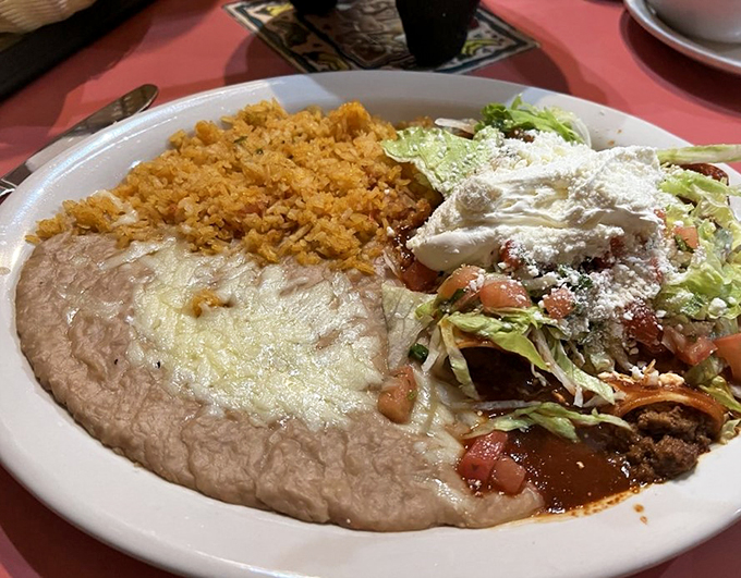 Classic comfort meets Mexican tradition with this hearty plate of rice, beans, and cheese-smothered enchiladas.