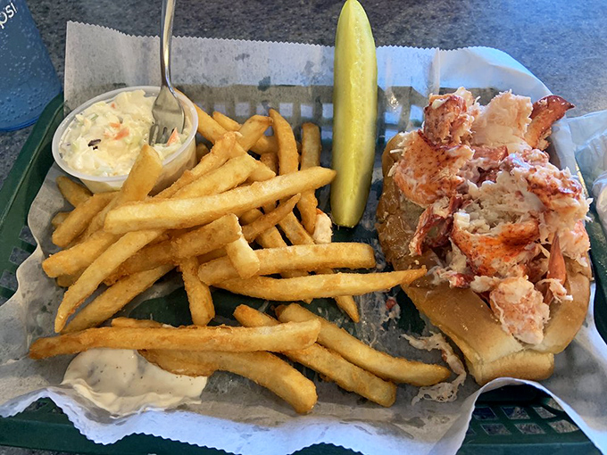 The classic Maine trio: lobster roll, crispy fries, and that essential pickle spear. A perfect seaside lunch.