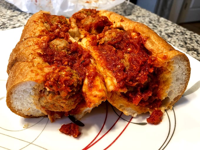 These meatballs aren't just sitting in sauce - they're lounging in a marinara hot tub on a fresh-baked submarine.