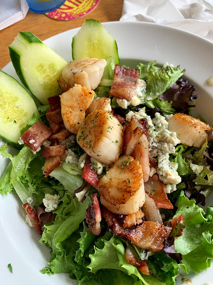 Garden-fresh greens playing host to perfectly seared scallops and crispy bacon &ndash; a salad that means business. Photo credit: Alison L.