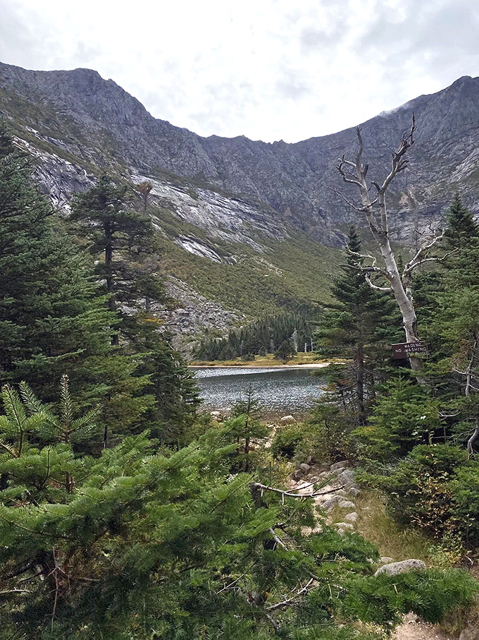 Granite cliffs frame Chimney Pond like nature's amphitheater, where the only performance is the daily dance of light and shadow.
