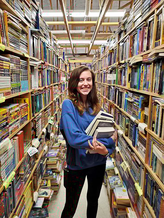 "When in doubt, grab an armful!" This happy bookworm demonstrates the proper technique for navigating Chamblin Bookmine's endless aisles.