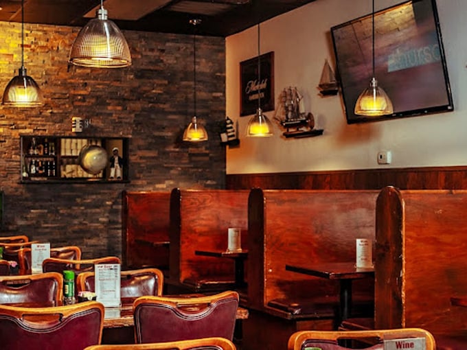 Rich wood booths and ambient lighting create the perfect backdrop for seafood storytelling and memory-making.