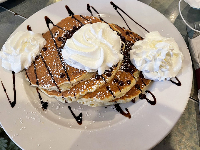 These pancakes wear their chocolate drizzle like formal wear, dressed up with whipped cream clouds of pure joy.