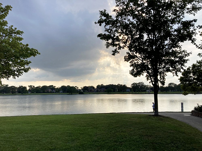 A lone figure finds solitude at sunset, proving sometimes the best company is a peaceful lake view.