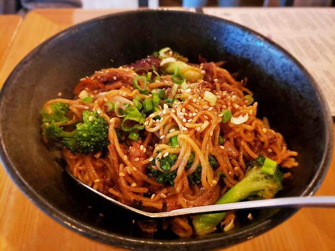 A tangle of noodles dressed in sauce, with broccoli adding pops of green like jewels in a crown.