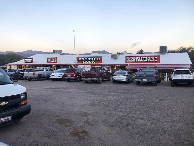 As the sun sets behind desert mountains, the Butcher Hook glows like a welcoming oasis for hungry travelers. 