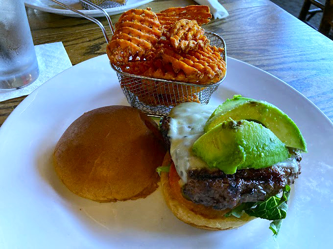 A burger that means business, topped with fresh avocado and served with waffle fries that look like they've earned their PhD in crispiness.