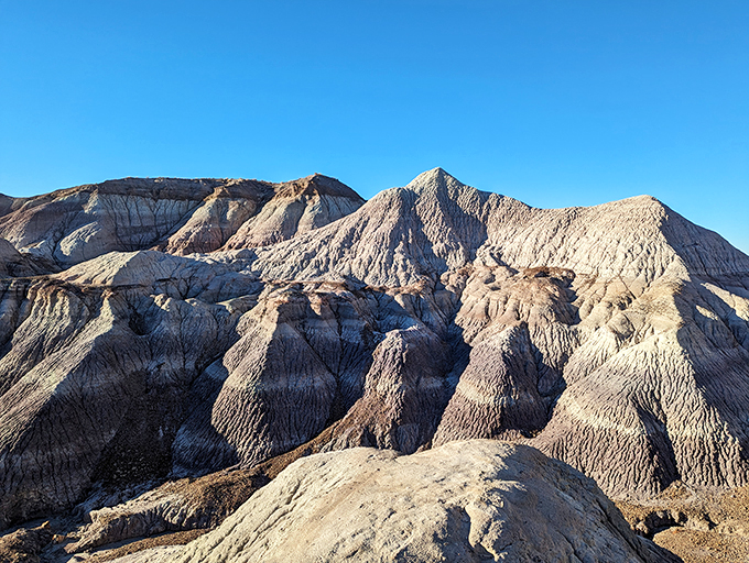 Layer cake of time! These striped hills tell Earth's story in vibrant hues, no frosting needed.