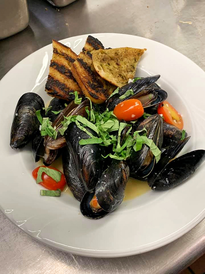 Fresh mussels swimming in aromatic broth, with grilled bread standing by for the delicious duty of soaking.