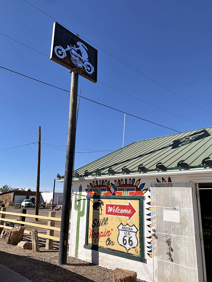 The motorcycle sign stands tall against endless blue skies, a beacon for road-weary travelers seeking authenticity.