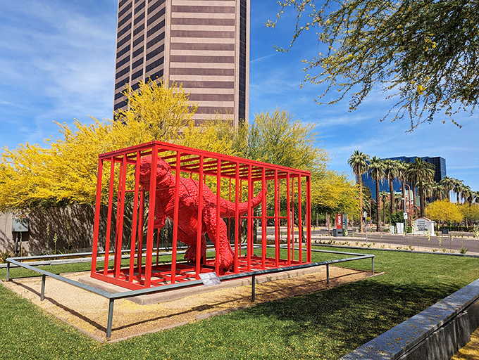 A bright red dinosaur basks in the Arizona sun, proving art can be both playful and profound.