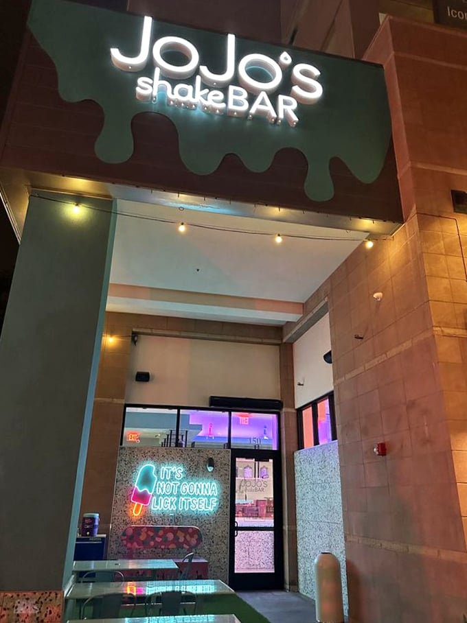 The dripping milkshake logo glows like a beacon, while the cheeky neon sign reminds us that good things take effort.