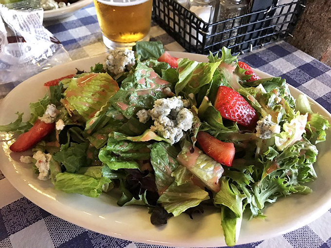 A fresh garden salad dotted with strawberries and blue cheese - because balance matters, even in seafood paradise.