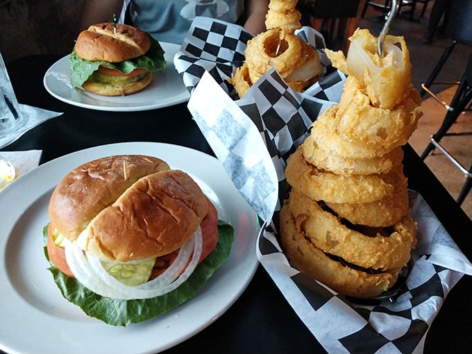 A tower of golden onion rings stands proudly beside classic burgers - proof that simple pleasures are often the most satisfying.