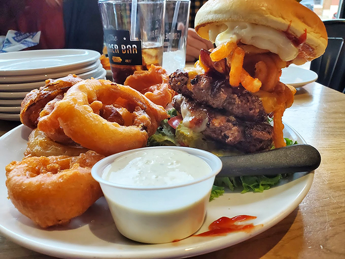 "Hold onto your buns!" This burger's stacked higher than a Jenga tower, with onion rings playing the role of delicious crown.