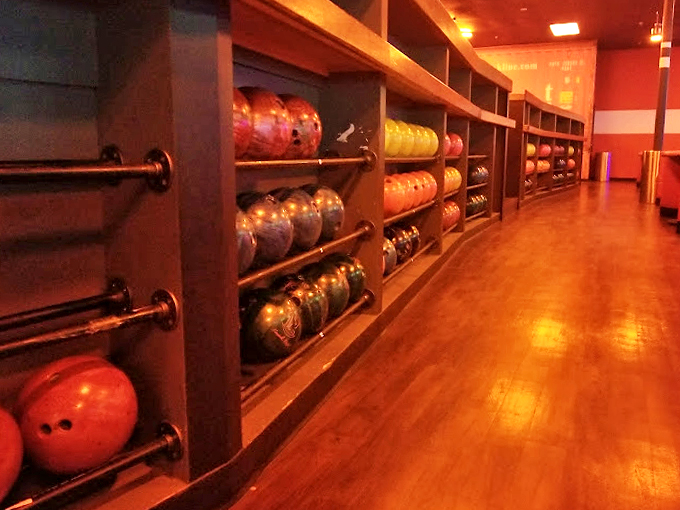 A rainbow of bowling balls awaits their moment of glory, lined up like colorful planets in a bowler's solar system.