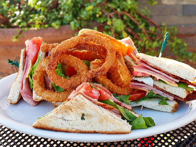 The club sandwich, stacked high with fresh ingredients and paired with crispy onion rings, demands your full attention. Photo credit: 5th Avenue Cafe