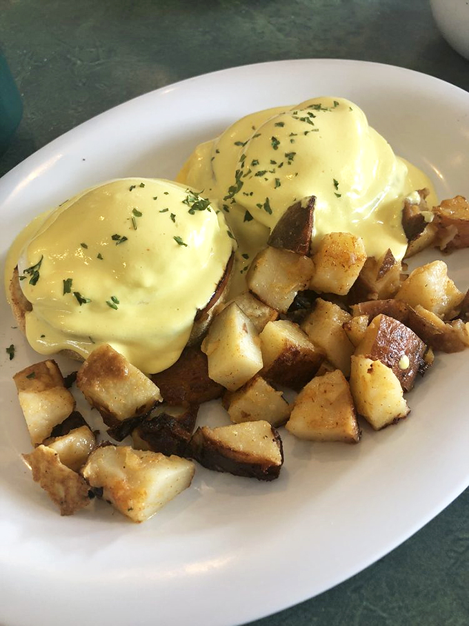 Eggs Benedict draped in hollandaise sauce like sunshine, with home fries that could convert a hash brown loyalist.