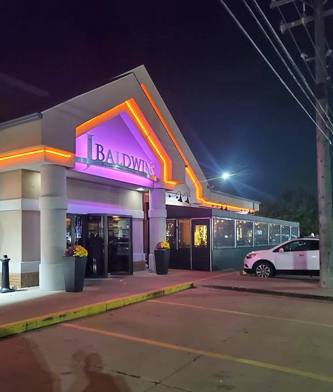 As night falls, J.Baldwin's transforms into a beacon of culinary excellence, glowing with purple and orange warmth. 