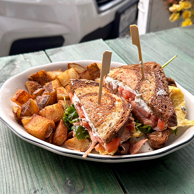 A towering sandwich creation served with perfectly seasoned home fries - lunch goals achieved.