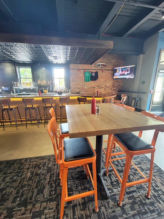 Exposed brick, warm wood, and vibrant orange chairs - this isn't just a bar, it's a cozy time capsule with beer on tap.