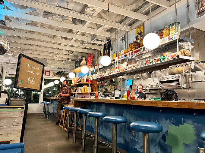 Sleek blue counter seating and warm wood surfaces blend retro charm with modern comfort under glowing globe lights.