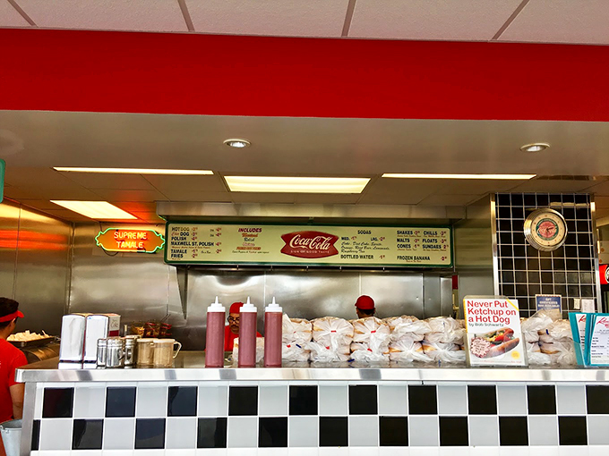 Behind that checkered counter, hot dog magic happens daily. The "No Ketchup" sign stands guard like a culinary constitution.