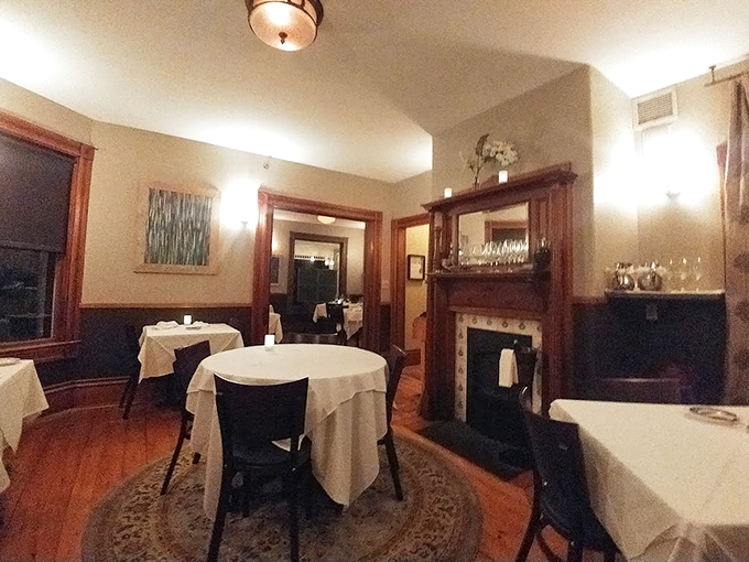 Warm wood trim and crisp white linens create an intimate dining space where even the fireplace seems to whisper, "Stay awhile." Photo credit: Jenifer Desquenne