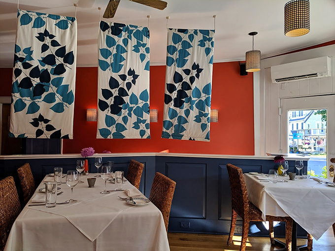 Elegant blue leaf patterns dance across coral walls while woven chairs invite you to settle in for an unforgettable meal.