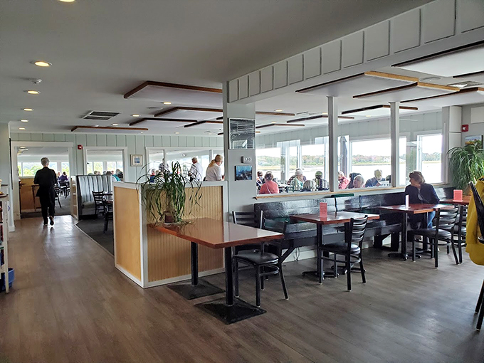 Sunlight streams through wall-to-wall windows, creating the perfect backdrop for seafood feasts while boats bob gently in the harbor beyond.