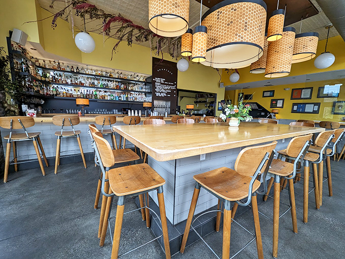 Honeycomb-patterned lampshades cast a warm glow over the communal table, while the well-stocked bar promises liquid courage for culinary adventures. Photo credit: Stephy Miehle