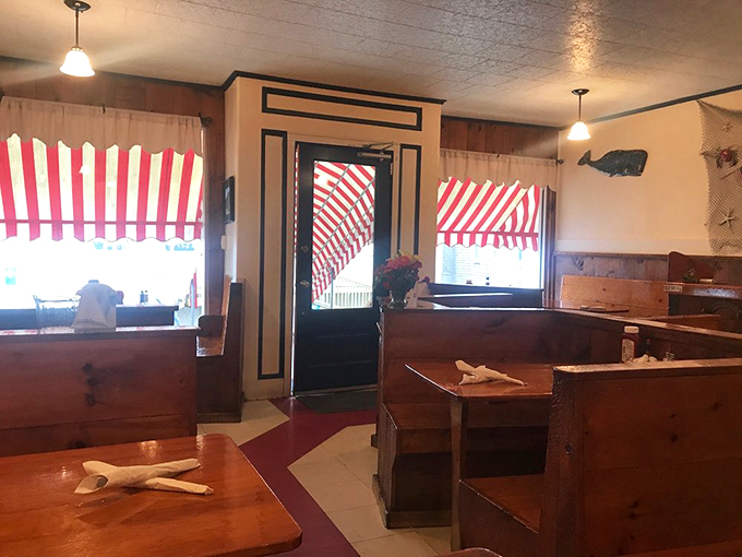 Red and white striped curtains dance with sunlight in this cozy dining room, where wooden booths tell tales of countless happy meals.