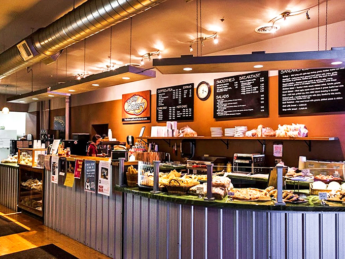 Modern industrial meets small-town charm with exposed ductwork and warm orange walls creating an inviting space for carb-lovers.