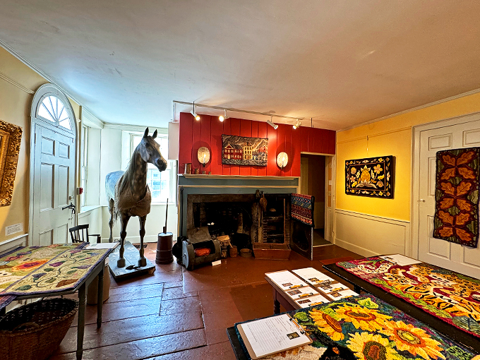 Where history meets whimsy - a life-sized horse statue holds court near a period fireplace, surrounded by colorful hooked rugs.