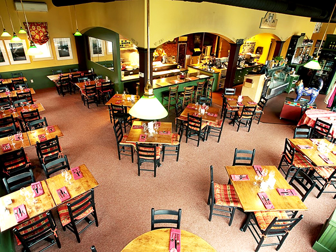 Warm yellow walls, forest green accents, and cozy wooden tables create an atmosphere that's part French bistro, part Vermont living room.