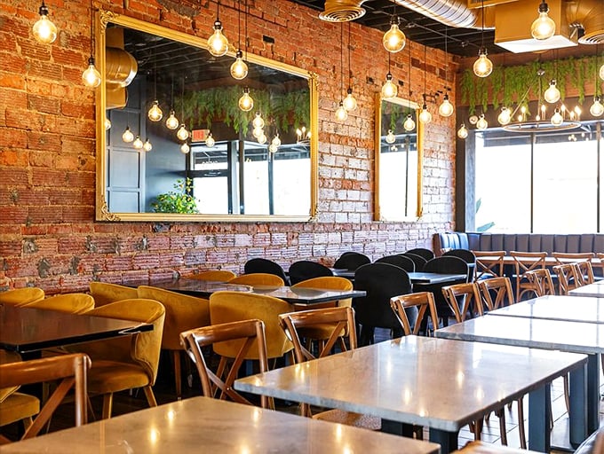 Edison bulbs dance across exposed brick walls while mustard-yellow banquettes invite you to stay awhile. Industrial chic meets cozy comfort.