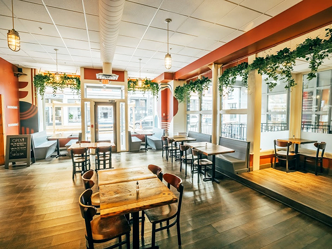Sunlight streams through tall windows, dancing across wooden tables while trailing plants create nature's chandelier in this warm, inviting space.