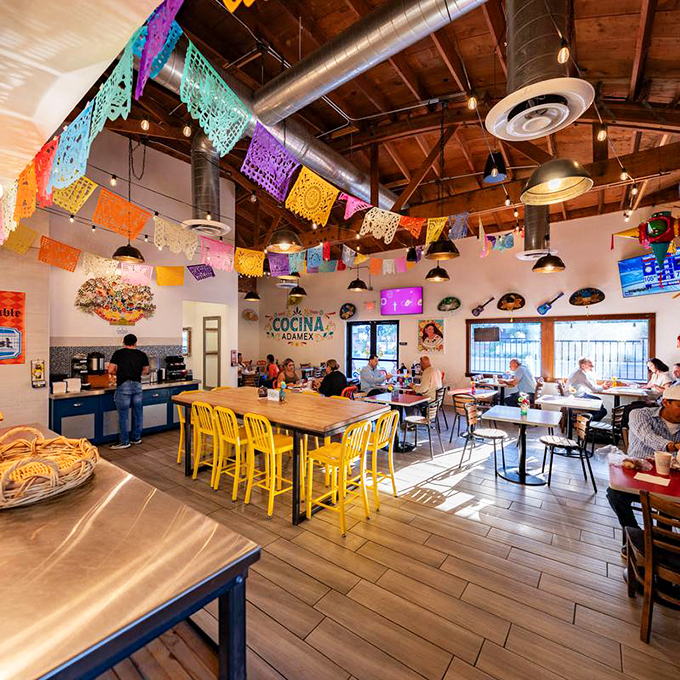Vibrant papel picado banners dance overhead while yellow chairs add sunshine to this cheerful dining room, creating an instant fiesta atmosphere.