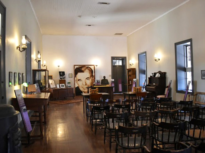 Wooden chairs await history enthusiasts in this beautifully preserved room, where vintage photographs and warm lighting create an intimate atmosphere.