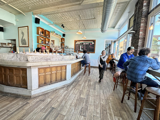 The curved oyster bar beckons like a pearl-studded stage, where seafood dreams come true under soft aqua walls.